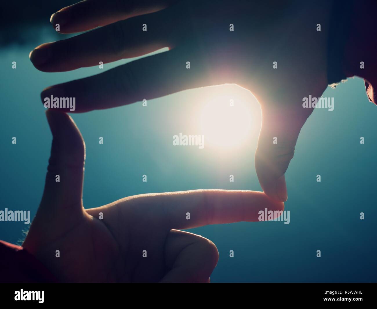 Female hands making finger shape gesture, hand holding sun flare at the ...