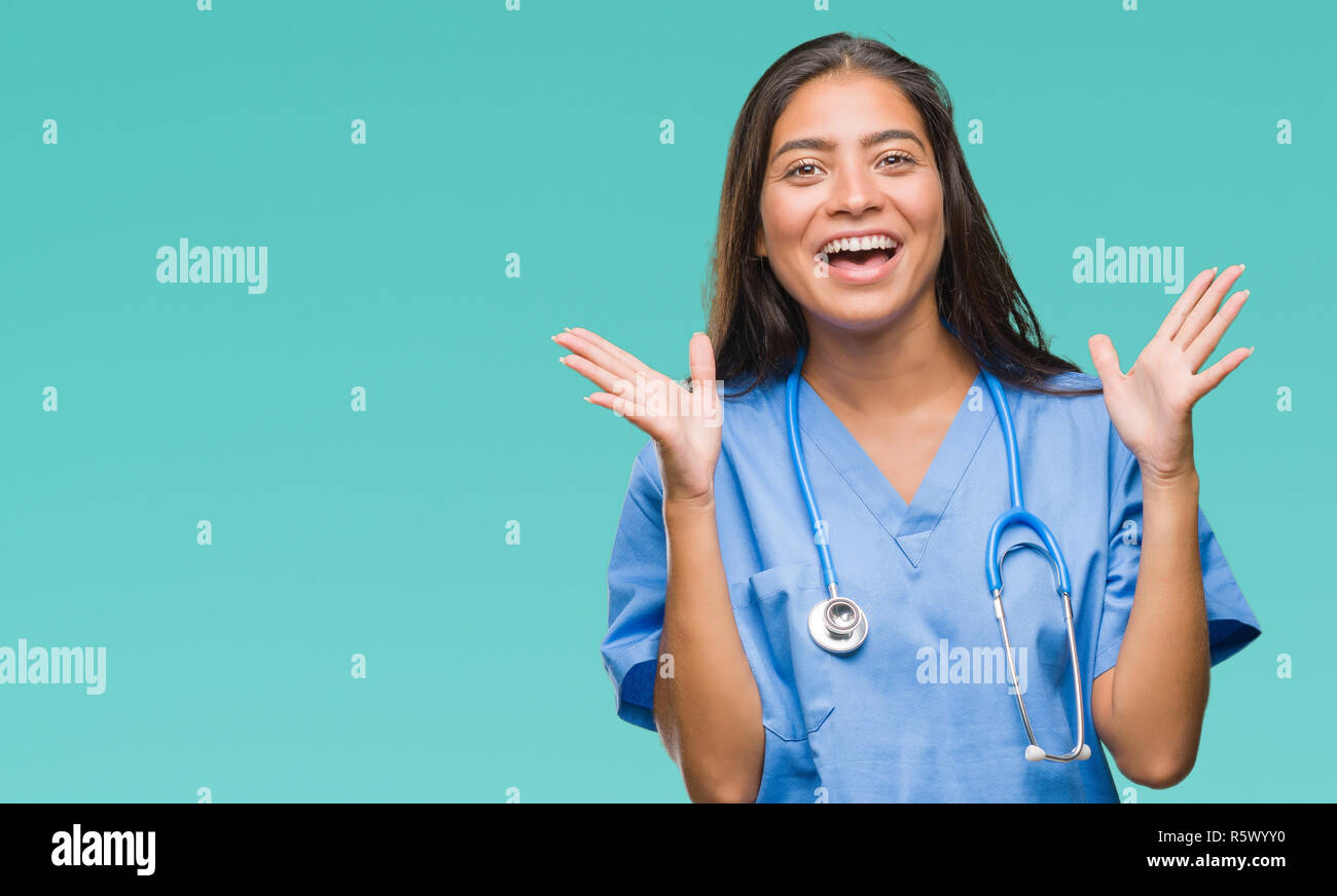 Young arab doctor surgeon woman over isolated background celebrating ...