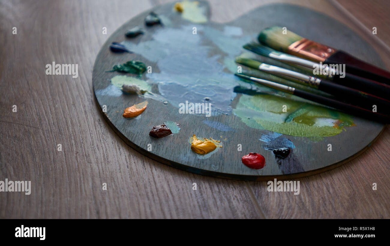 Artist palette with oil paints and brushes on a wooden background ...