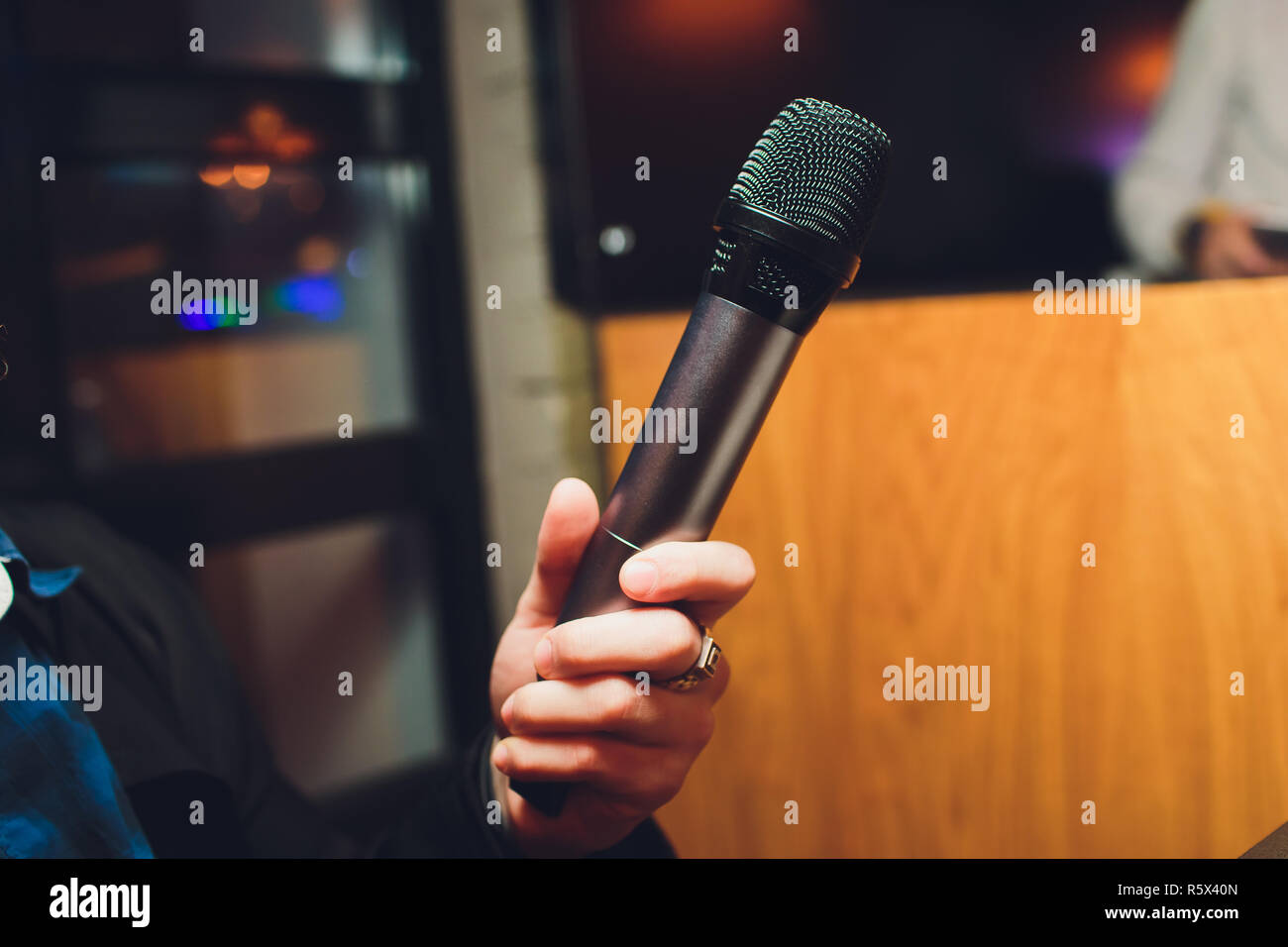 Close up male hand holding microphone. in the interior of the bar Stock ...