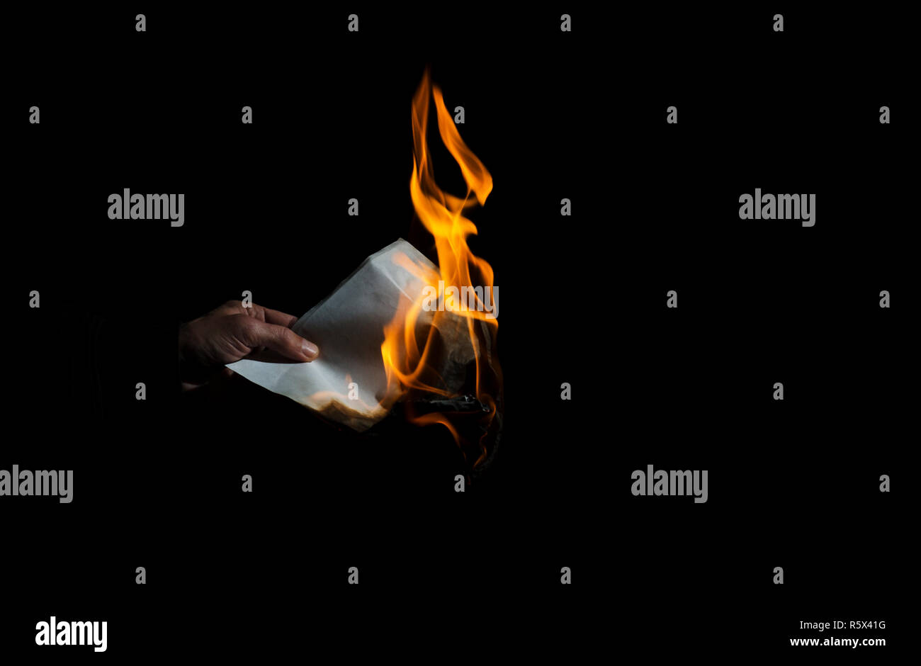 Burning a piece of paper in a man's hand on a black background Stock ...