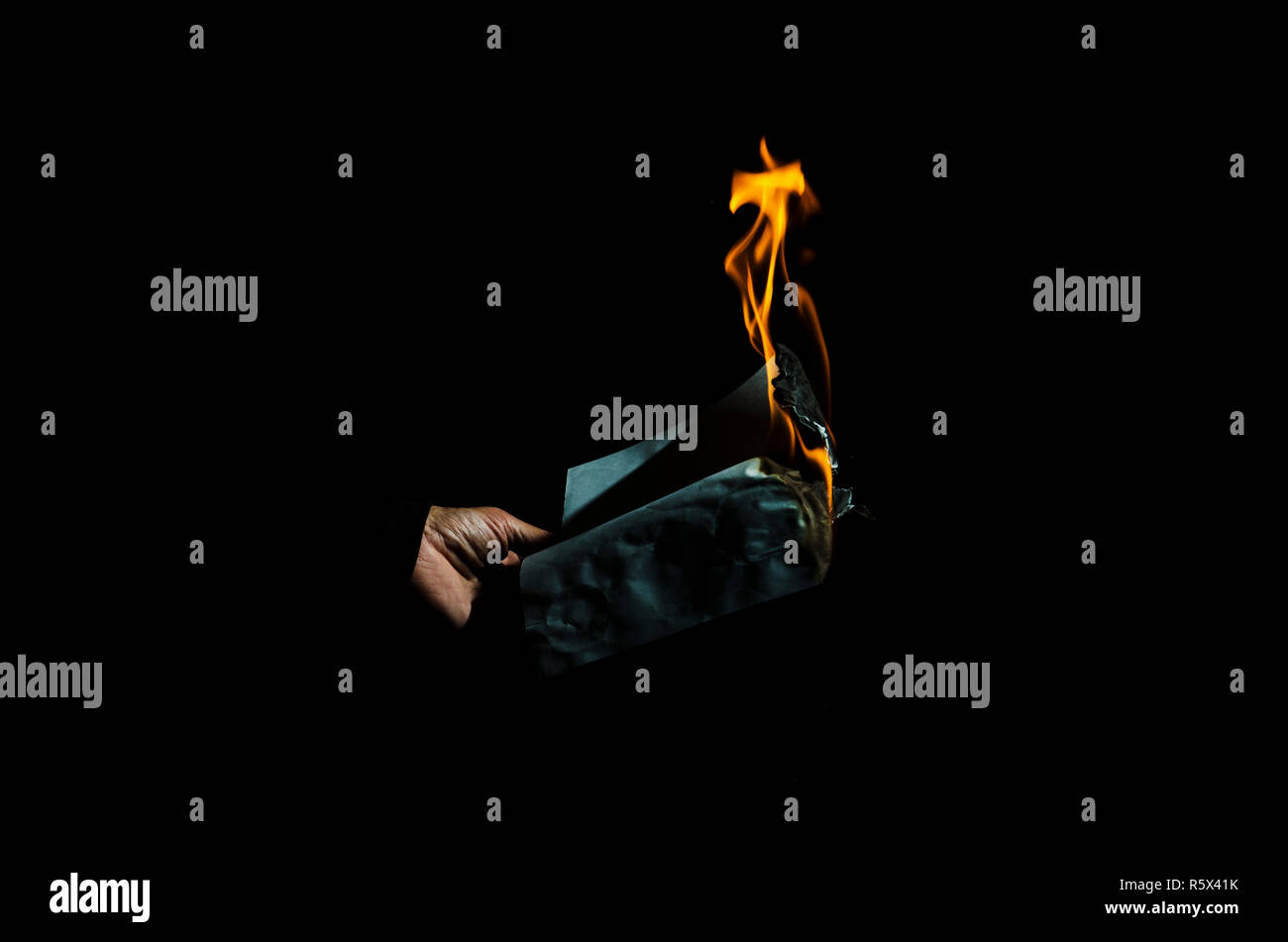 Burning a piece of paper in a man's hand on a black background Stock ...