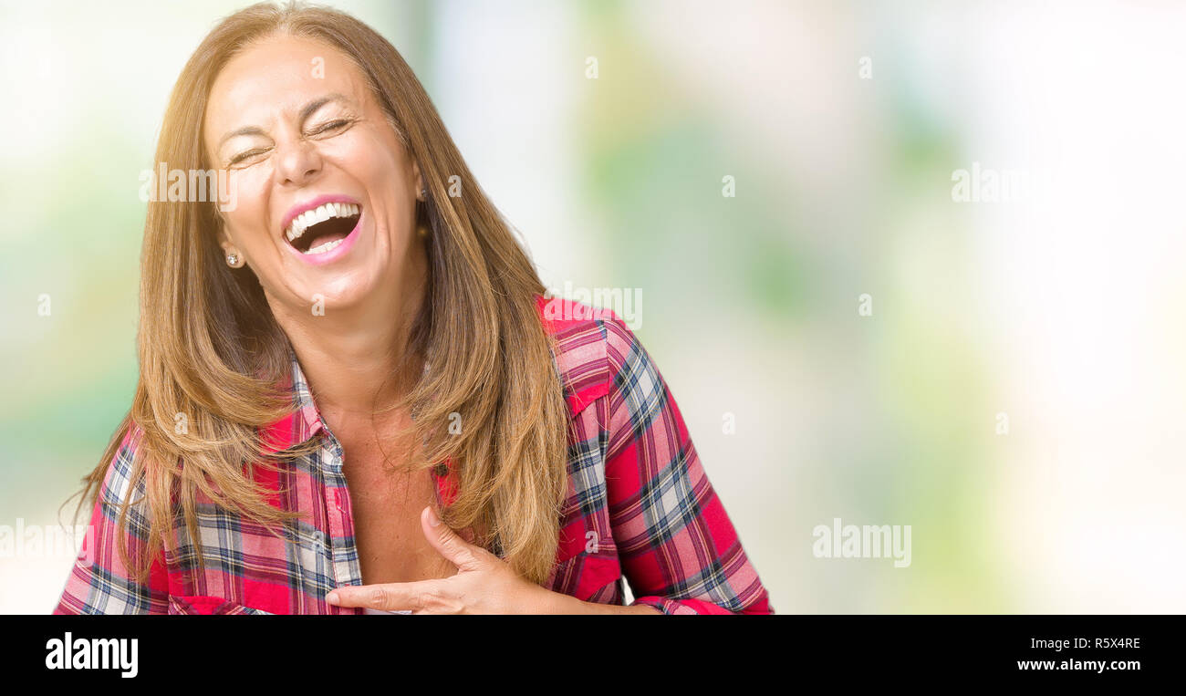 Beautiful middle age woman wearing over isolated background Smiling and laughing hard out loud ...