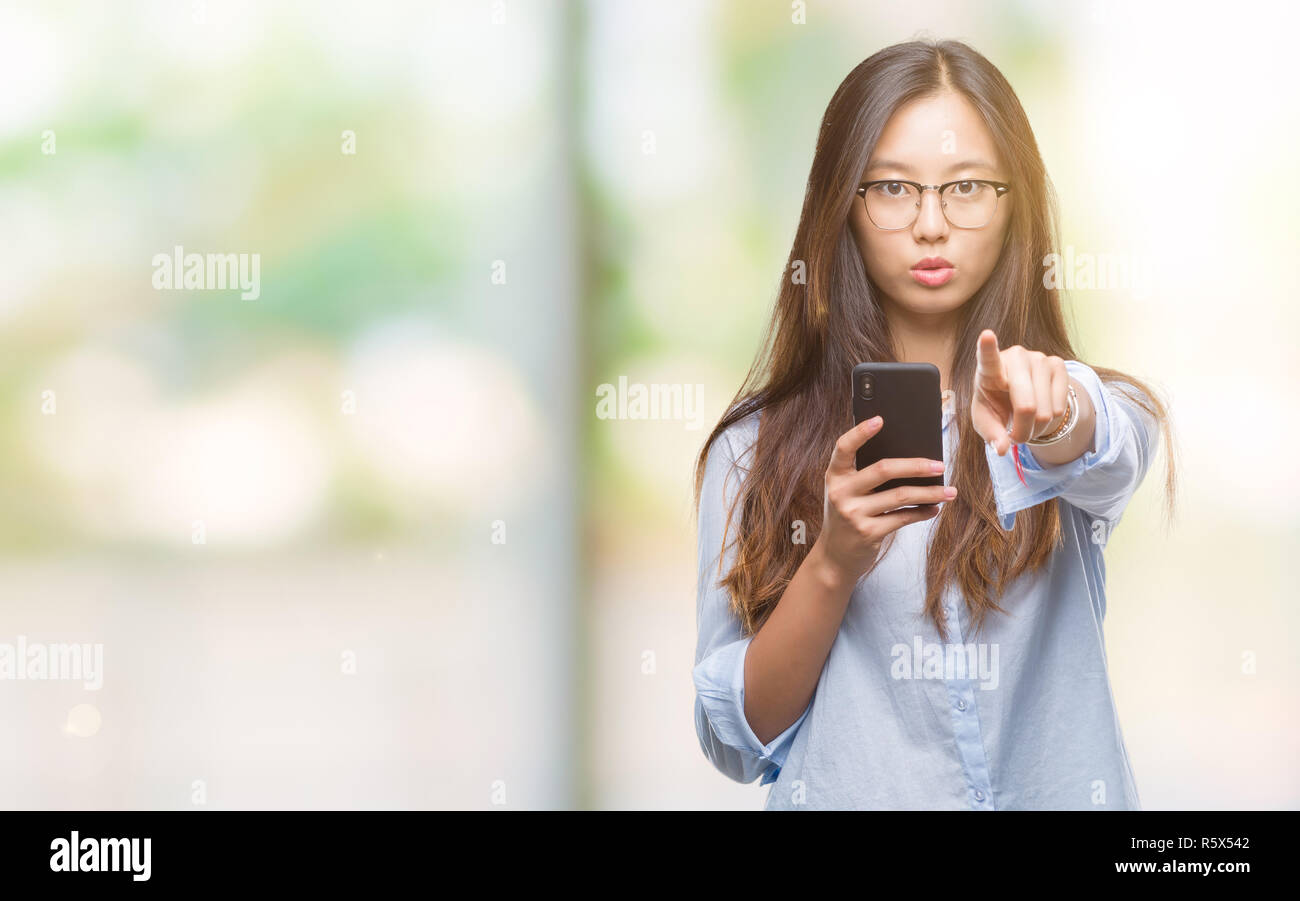 Young asian woman texting using smartphone over isolated background ...