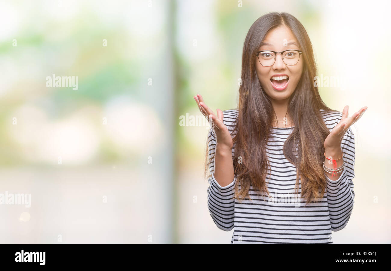 Young asian woman wearing glasses over isolated background celebrating ...