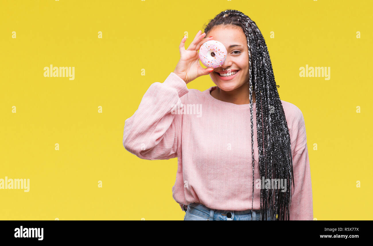 Young african american girl eating pink donut over isolated background ...