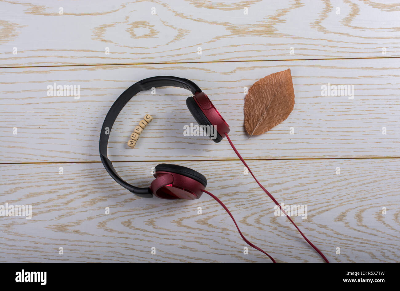 Dice-sized alphabet cubes spelling music, dried leaf and red headphones ...