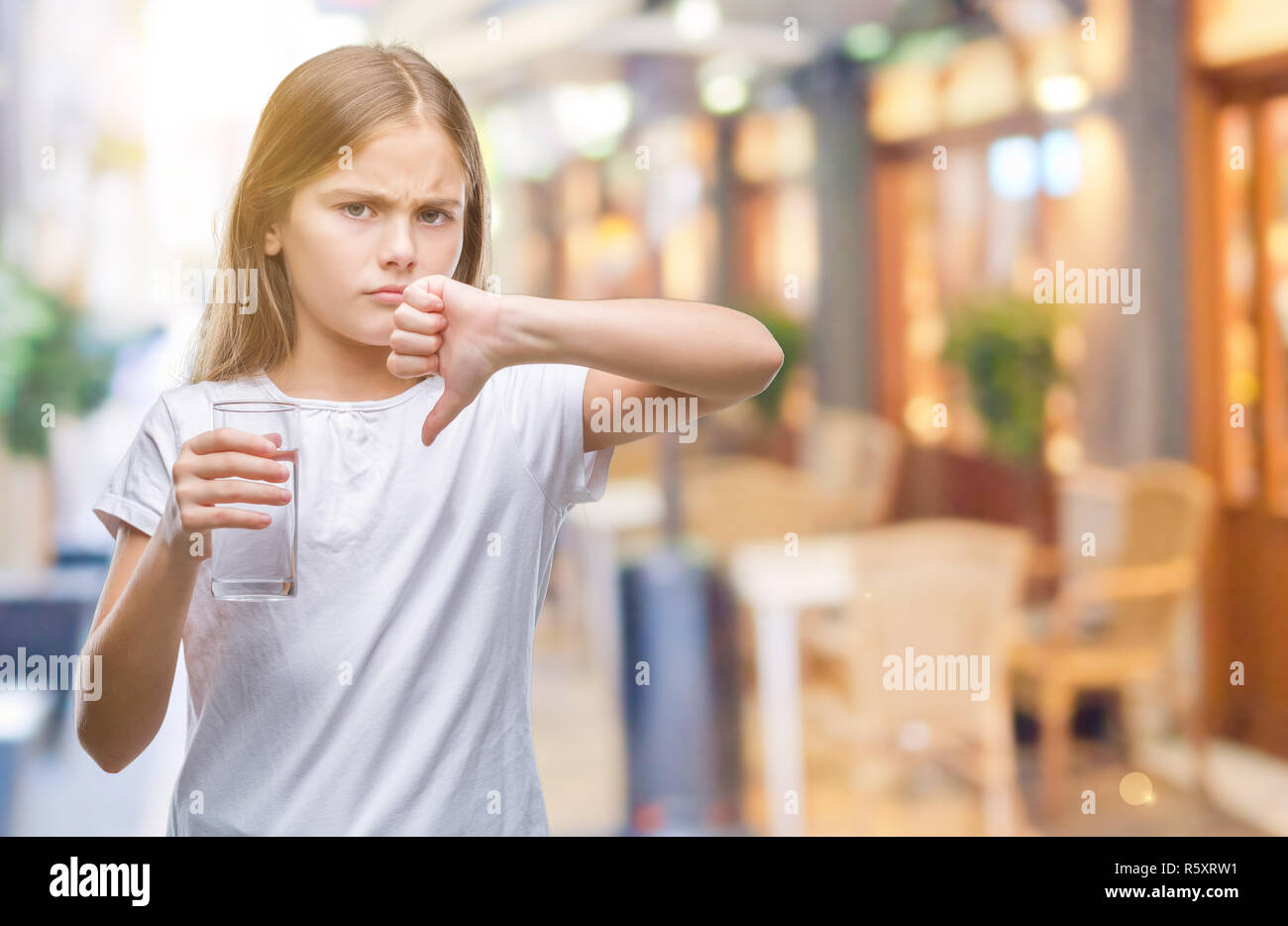 Young beautiful girl drinking glass of water over isolated background ...