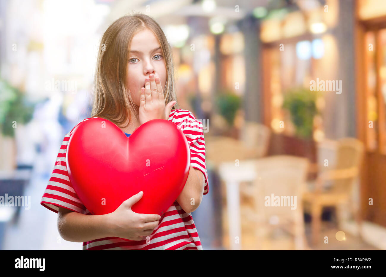 Young beautiful girl holding red heart over isolated background cover ...