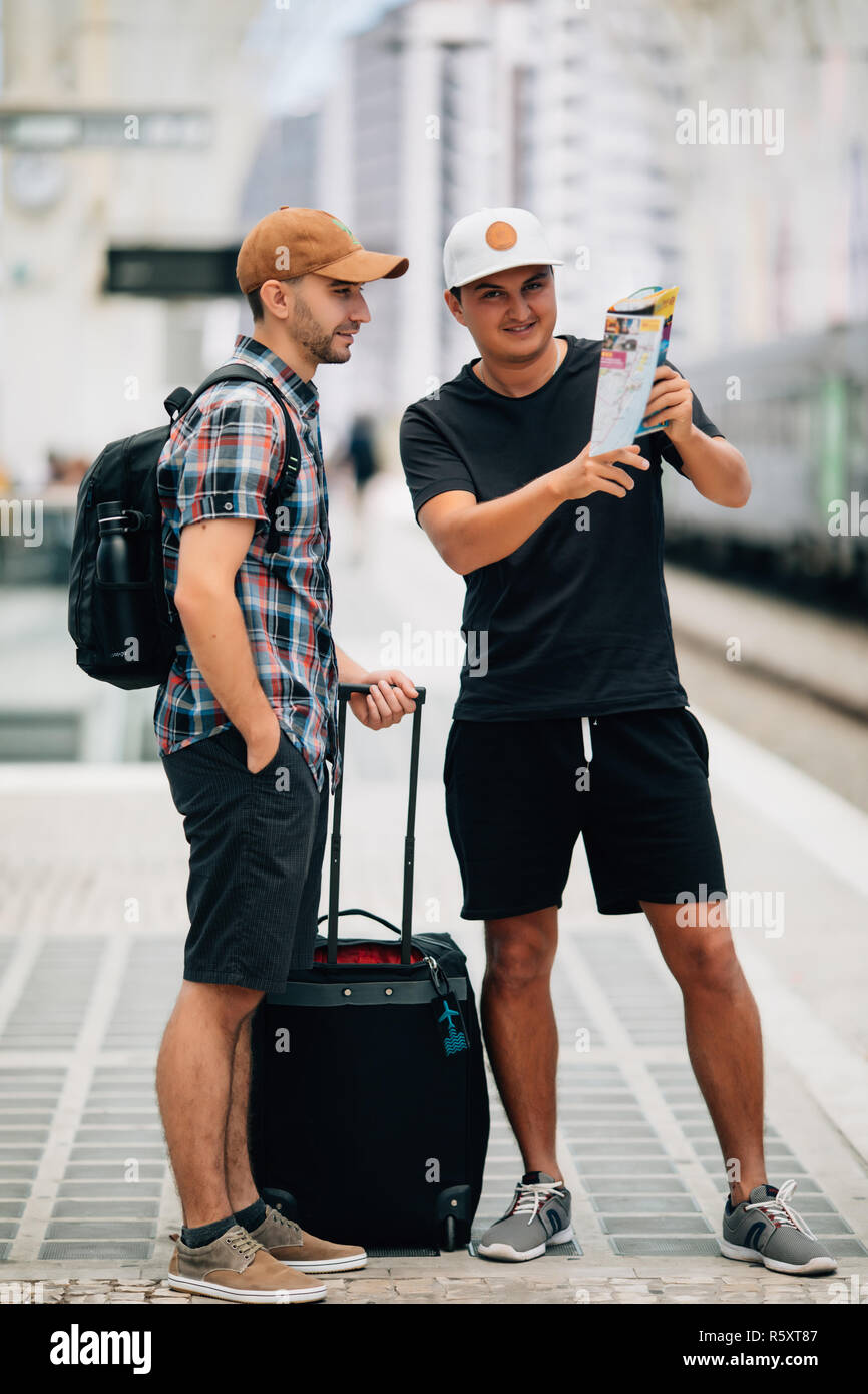 Two backpackers look at a map at train station Stock Photo - Alamy