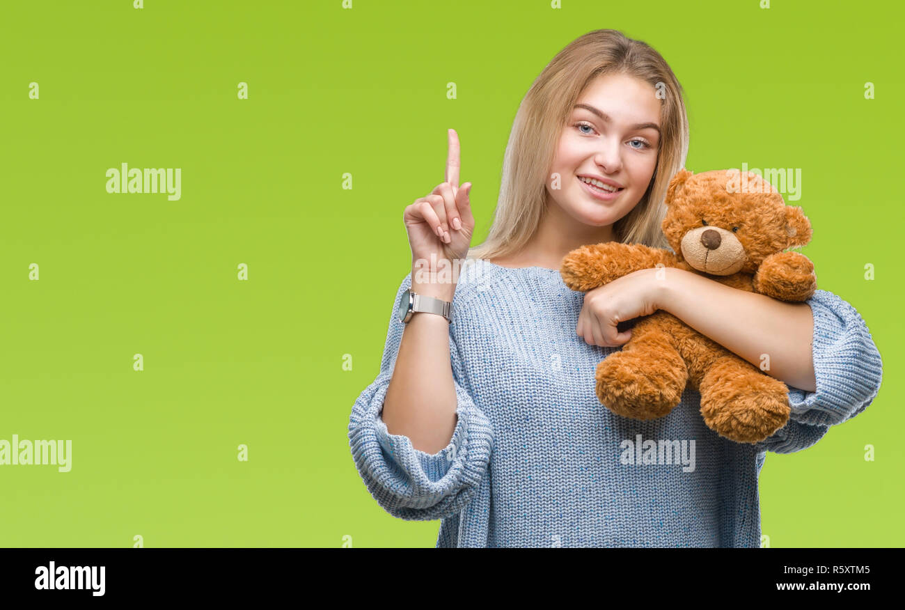 Young caucasian woman holding cute teddy bear over isolated background ...