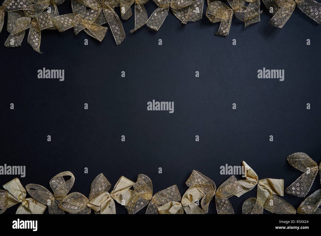 Flat lay of golden gift bows on dark background. New year and christmas ...