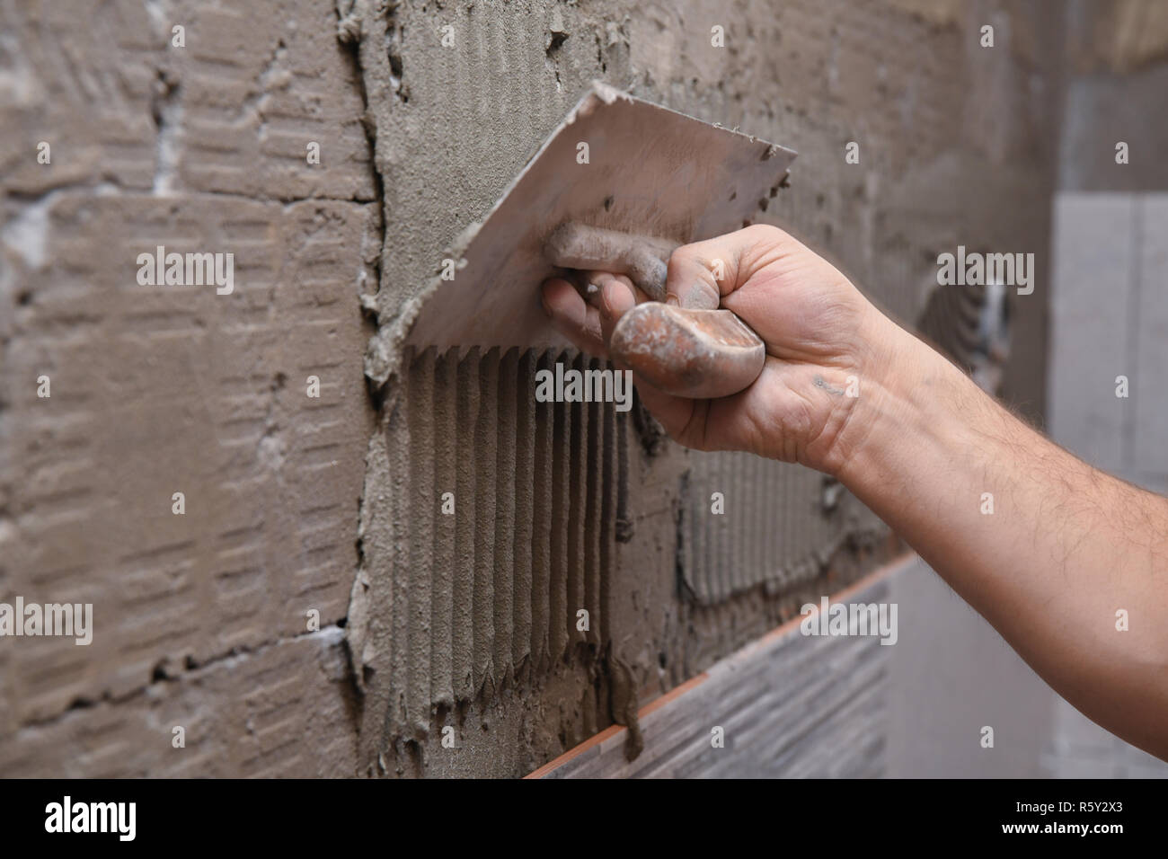 Professional constructor applying glue before laying ceramic tiles on ...