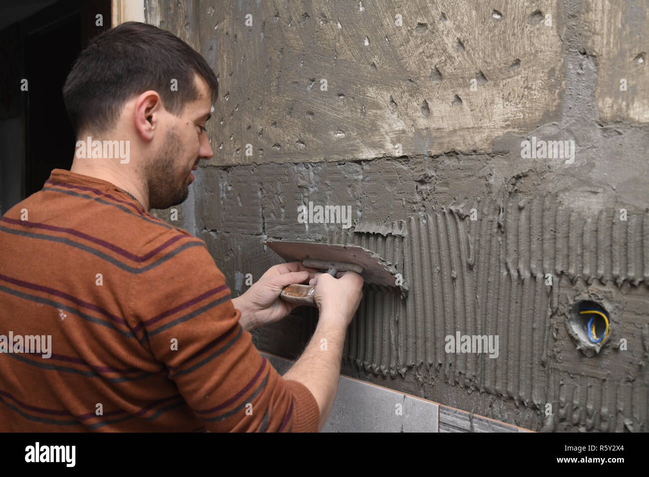Professional constructor applying glue before laying ceramic tiles on ...