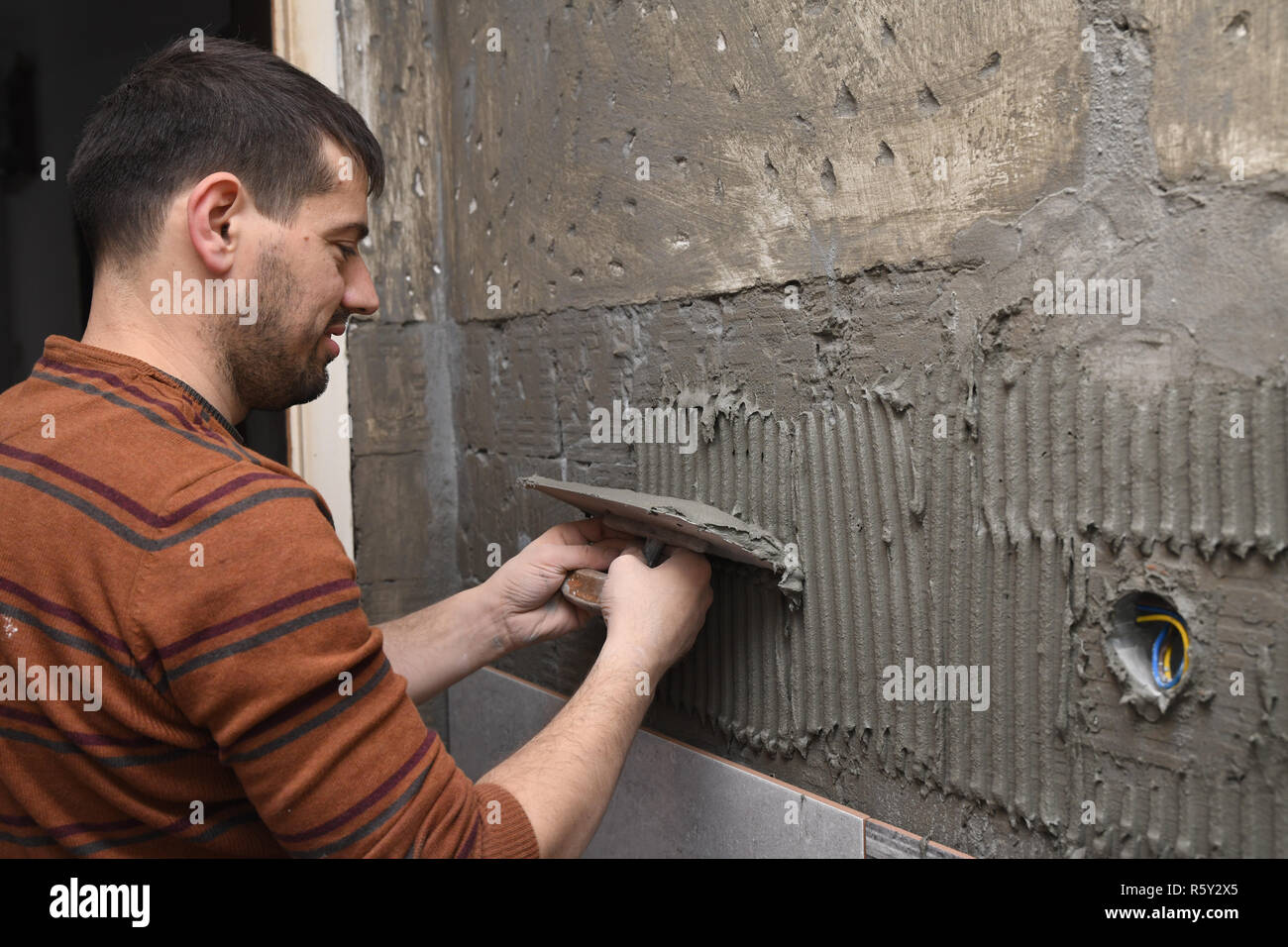 Professional constructor applying glue before laying ceramic tiles on ...