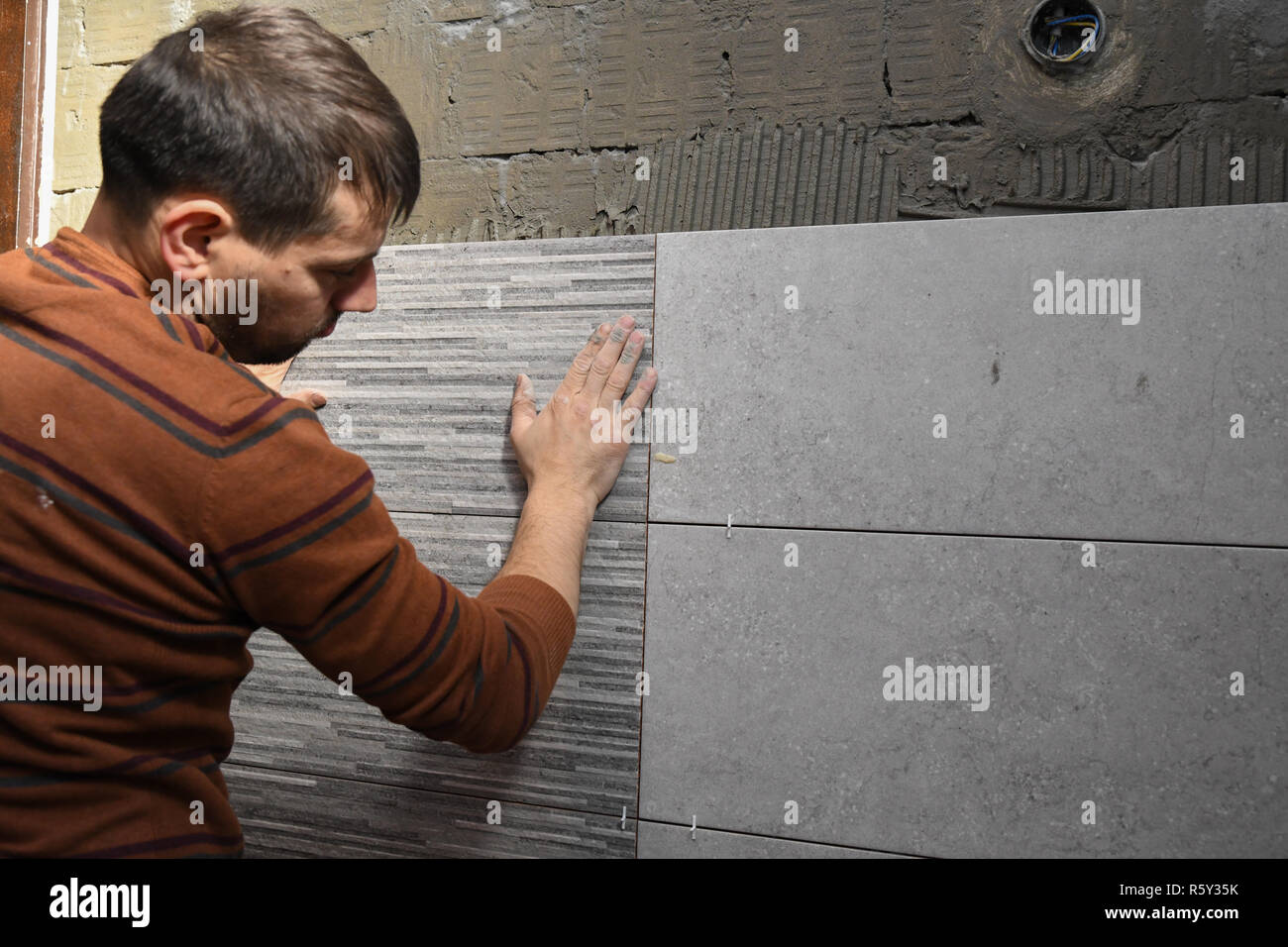 Gluing tiles on the wall. Laying tiles on the wall. Worker installing ...
