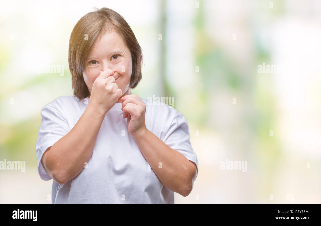 Young adult woman with down syndrome over isolated background smelling ...