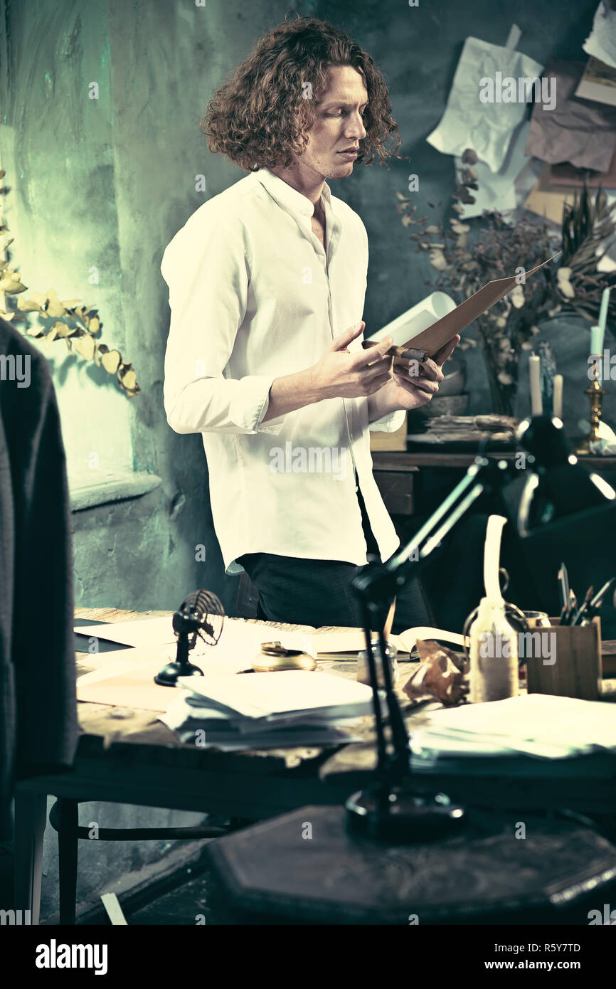 Writer at work. Handsome young writer standing near the table and ...