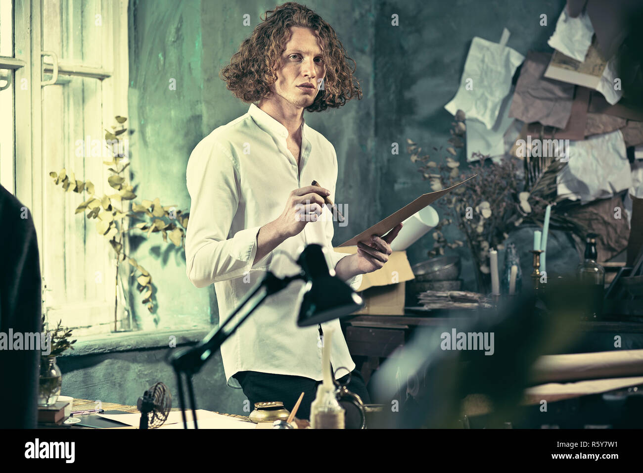 Writer at work. Handsome young writer standing near the table and ...