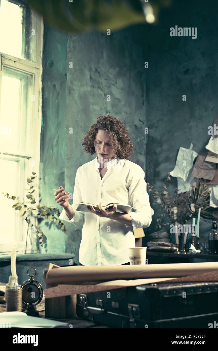 Writer at work. Handsome young writer standing near the table and ...