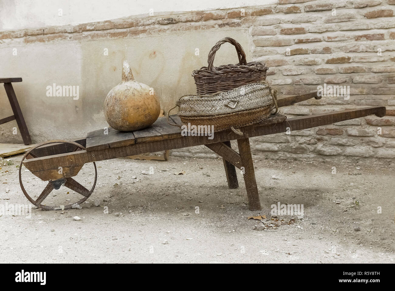 outdoor scene with an antique wooden wheelbarrow with iron wheel ...