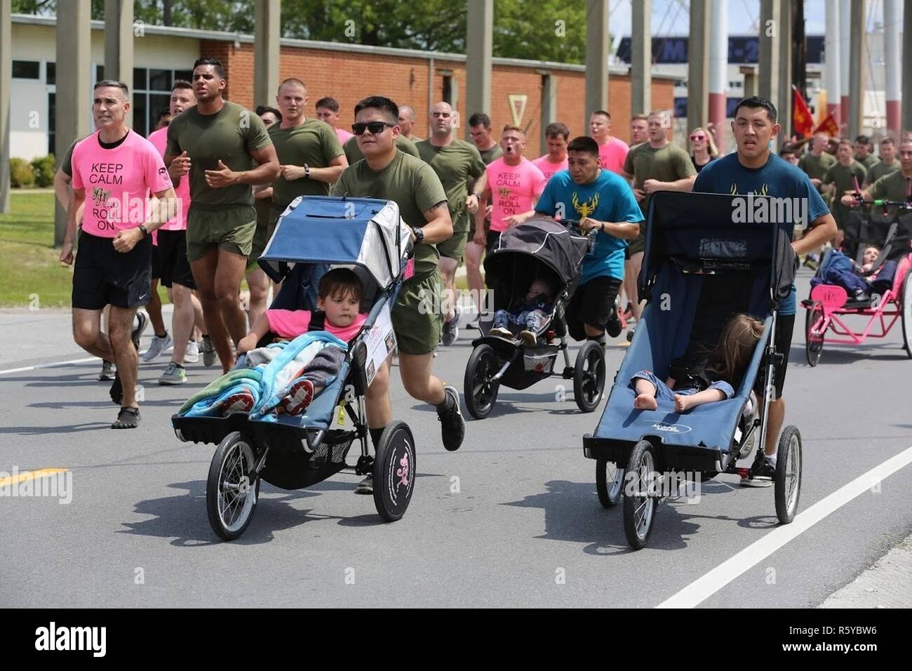 Marines push athlete riders along side other Marines during a formation ...