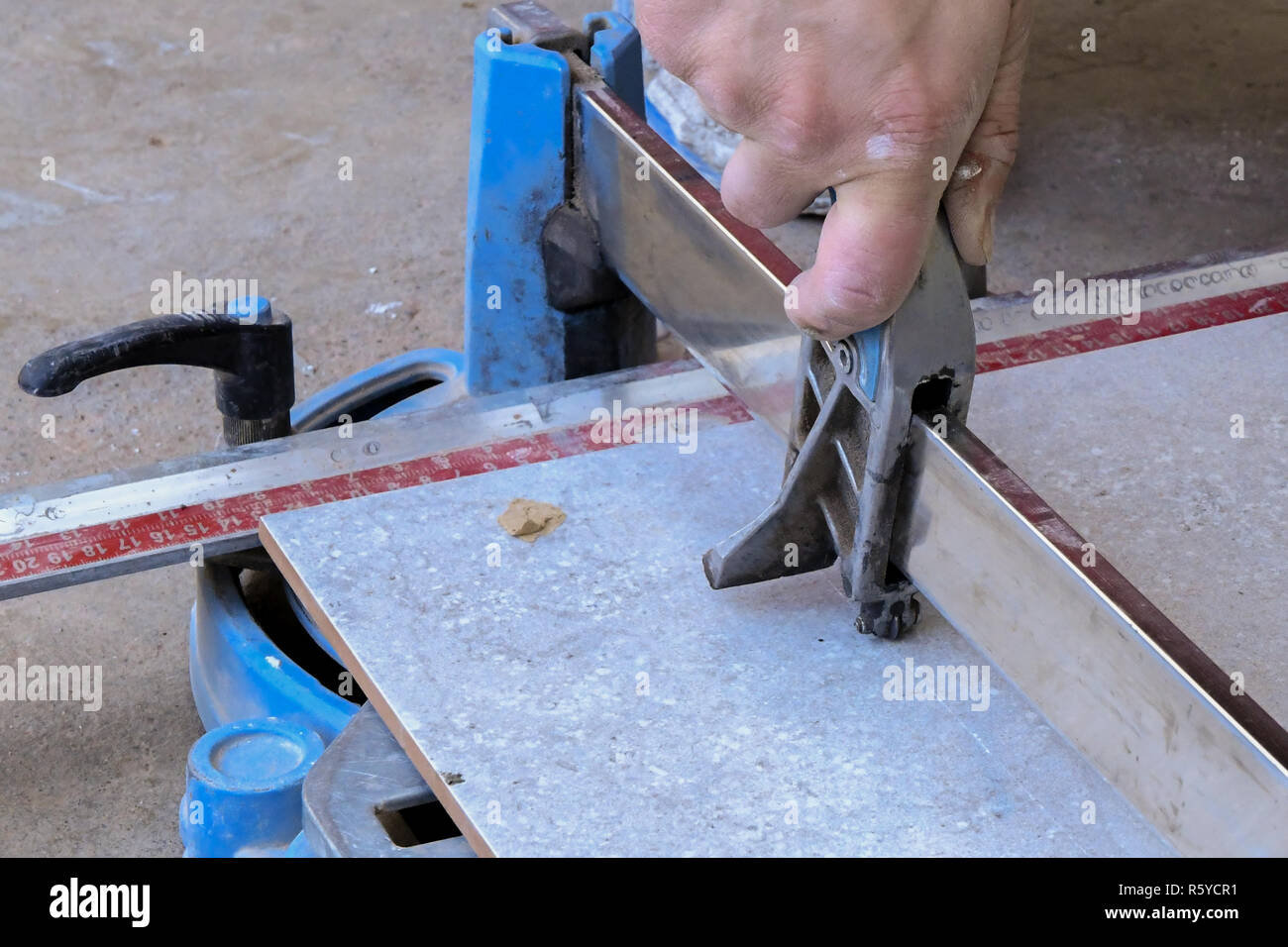 Cutting ceramic tile. Worker placing a big ceramic tile in a cutter and ...