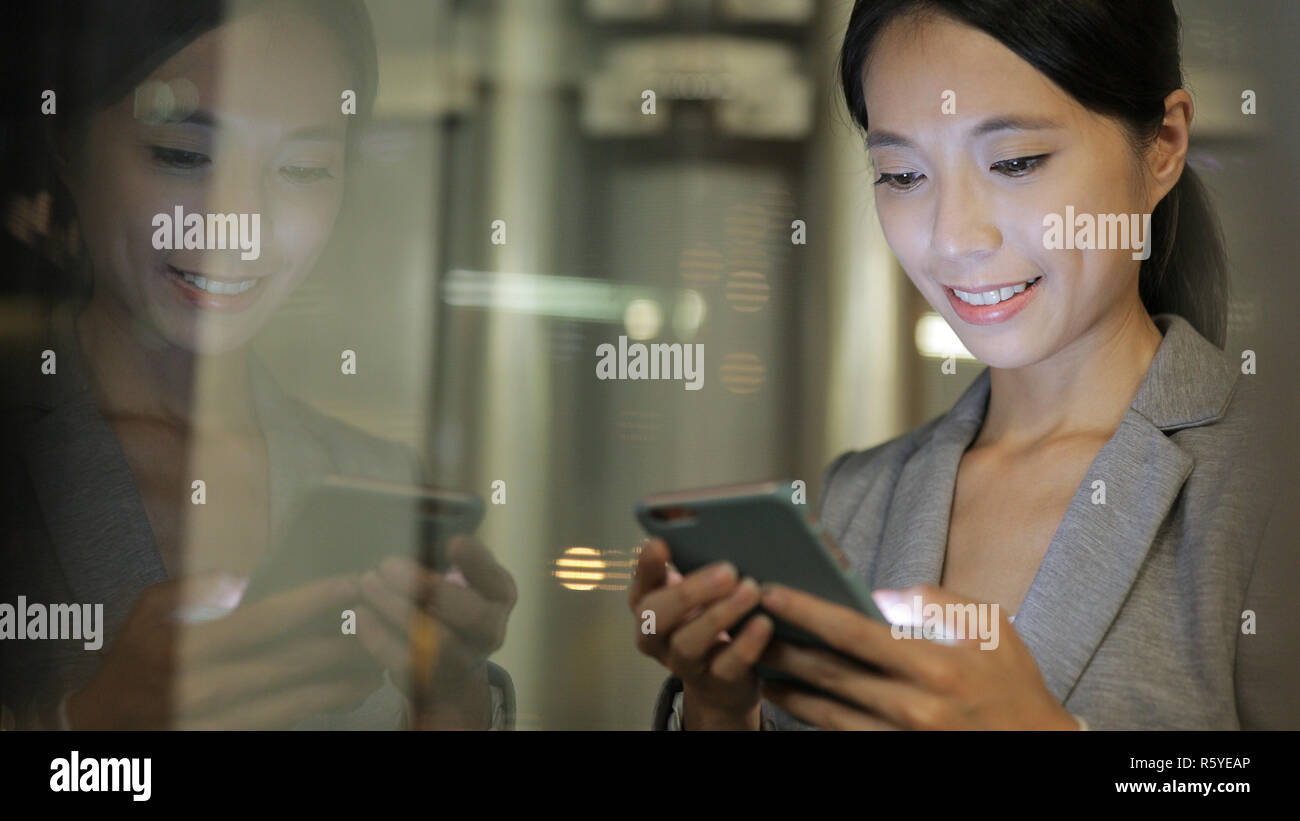 Business woman reply client email on cellphone with window reflection ...