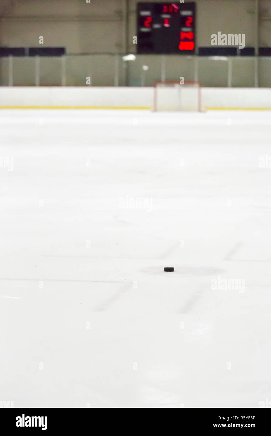 Hockey puck in empty ice rink Stock Photo - Alamy