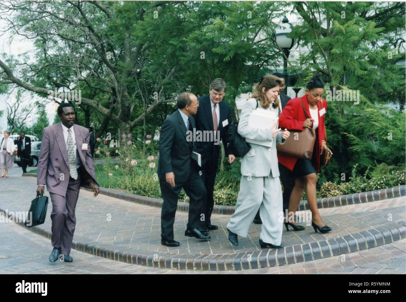 A GROUP OF MEN AND WOMEN ARE WALKING TOGETHER ON THE SIDE WALK Stock ...