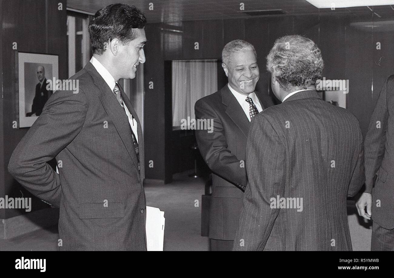 TWO MEN GREETING EACH OTHER WITH OTHER MEN WATCHING Stock Photo - Alamy