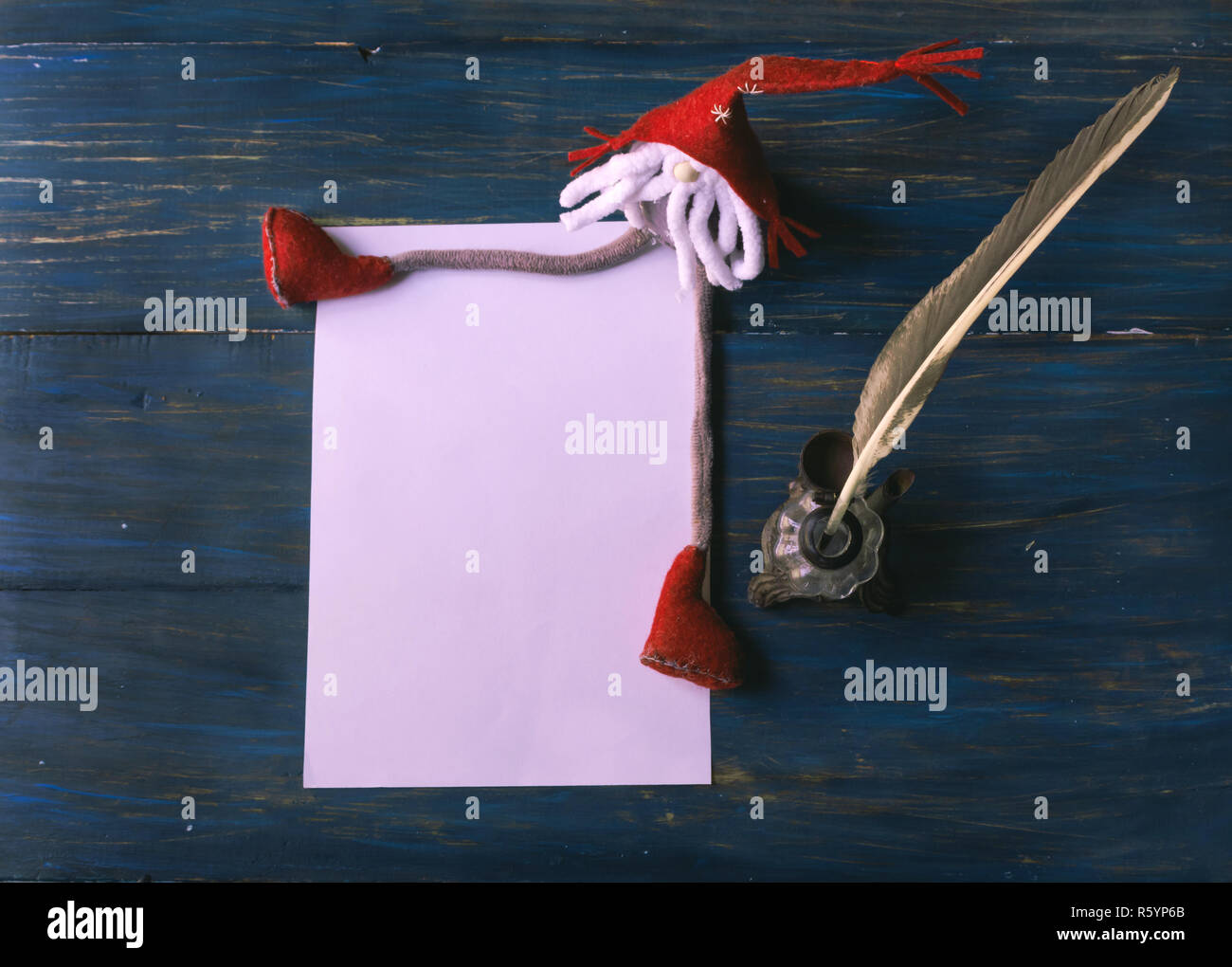 Empty letter with a feather and inkwell on an old blue wooden ...