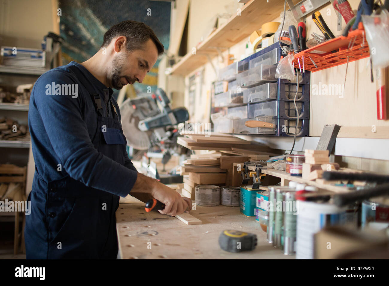 Side view portrait of mature carpenter working with wood in modern ...