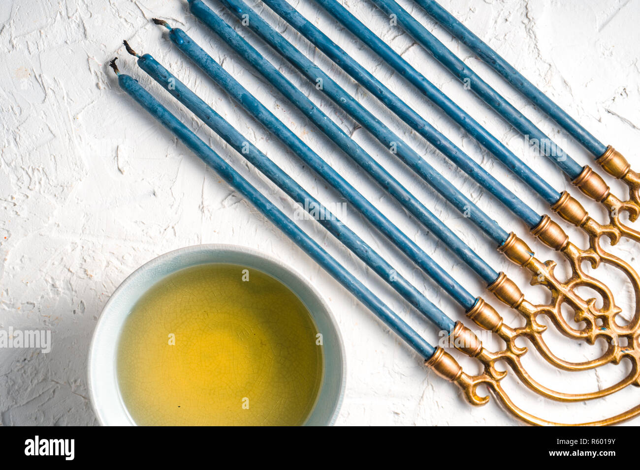 Brass Hanukiya Menorah with blue candles and butter in a bowl diagonal ...