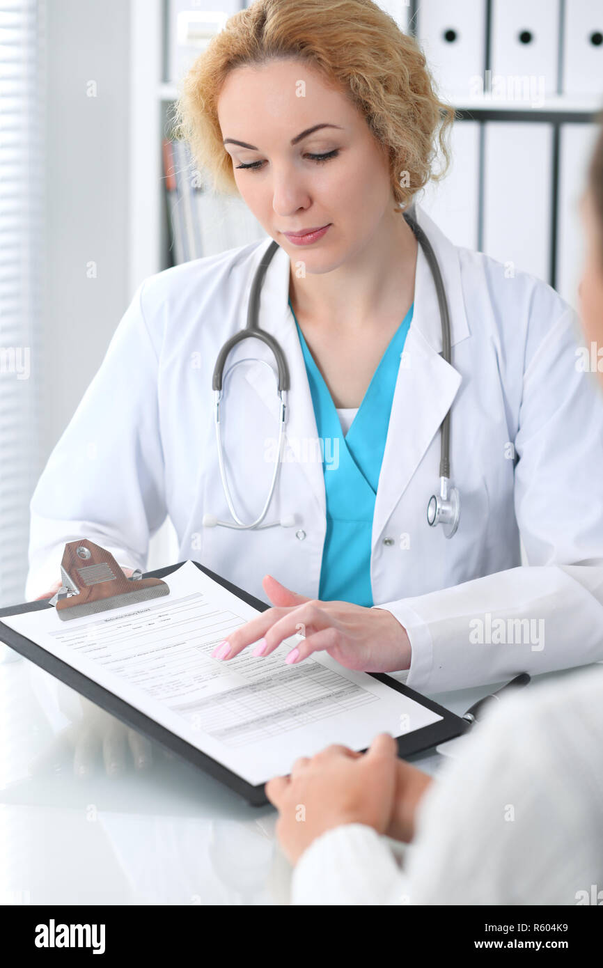 Happy blonde female doctor and patient discussing medical examination ...