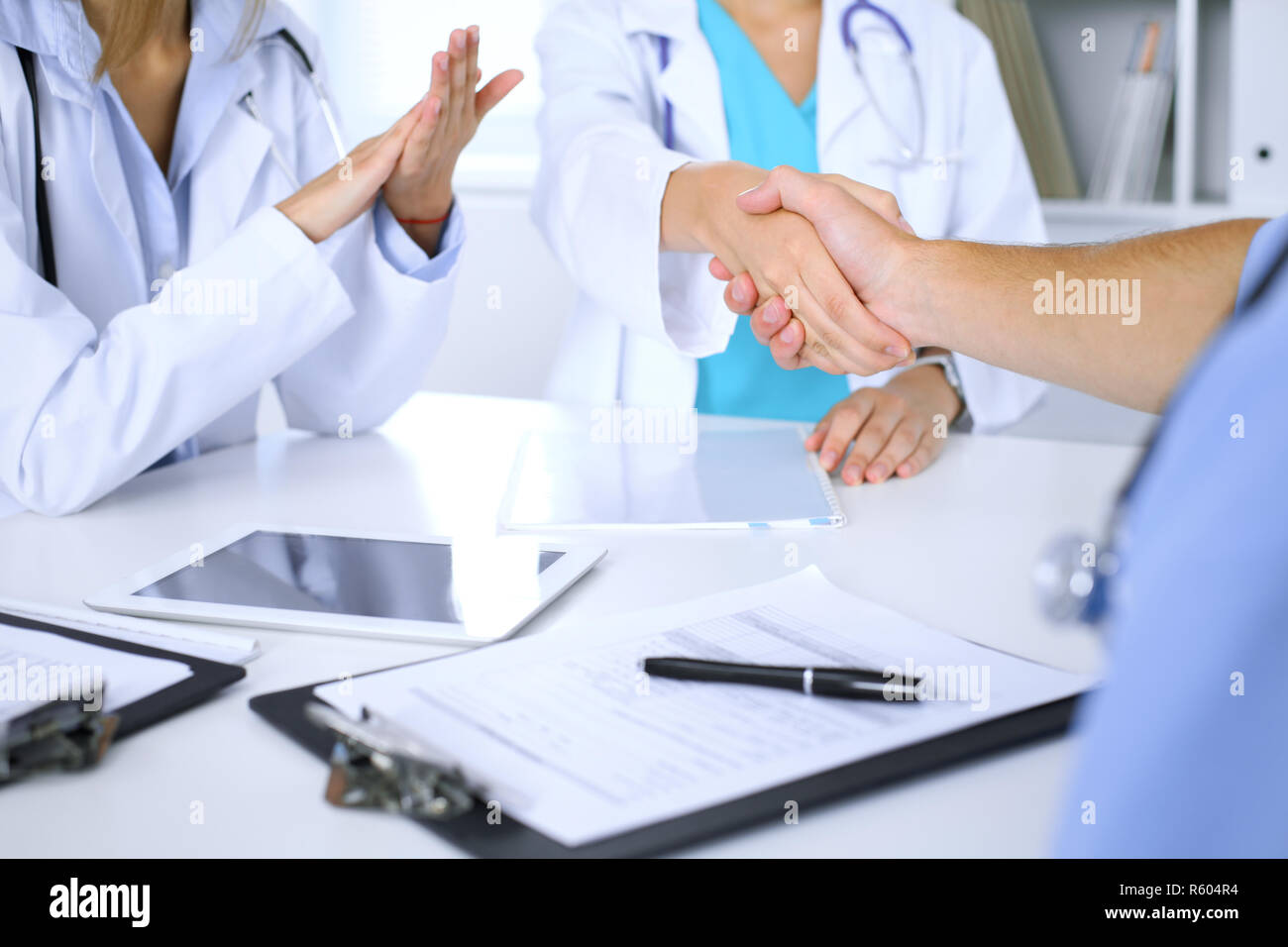 Two doctors shaking hands to each other at meeting. Teamwork and ...