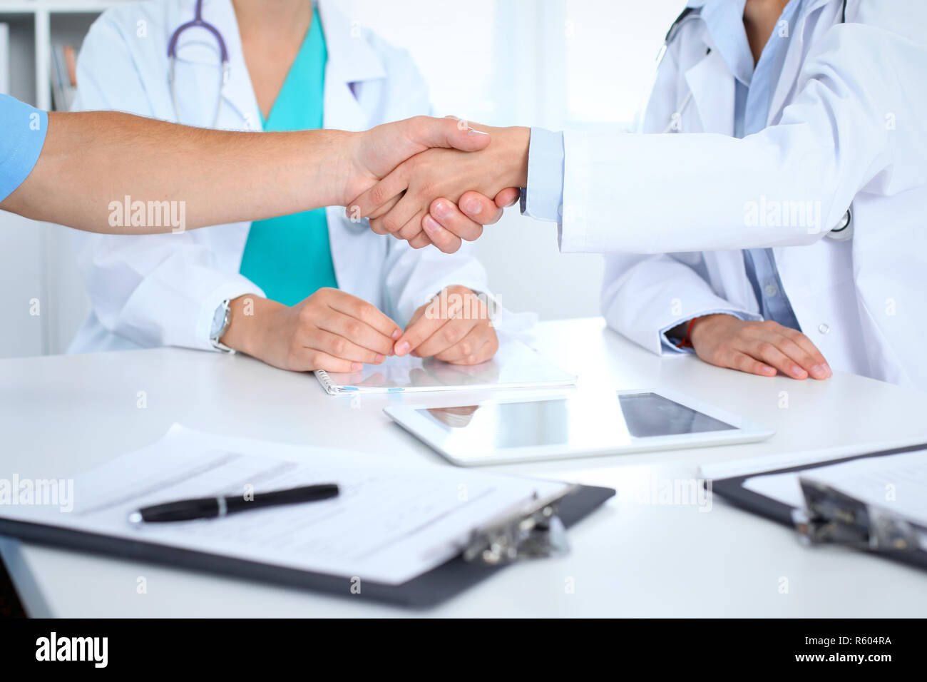 Two doctors shaking hands to each other at meeting. Teamwork and ...
