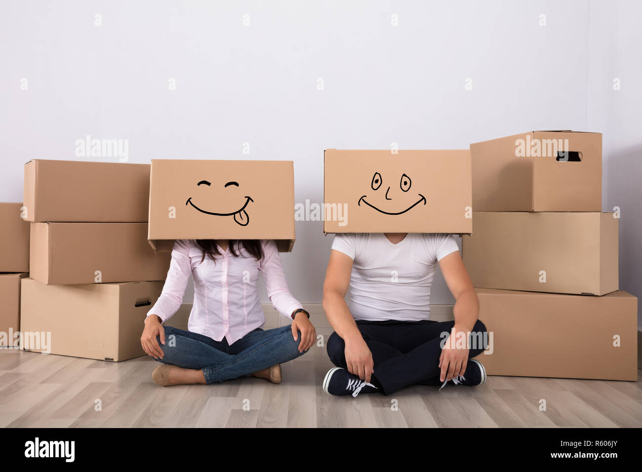 Happy Couple Lying On Floor Wearing Cardboard Boxes Stock Photo - Alamy