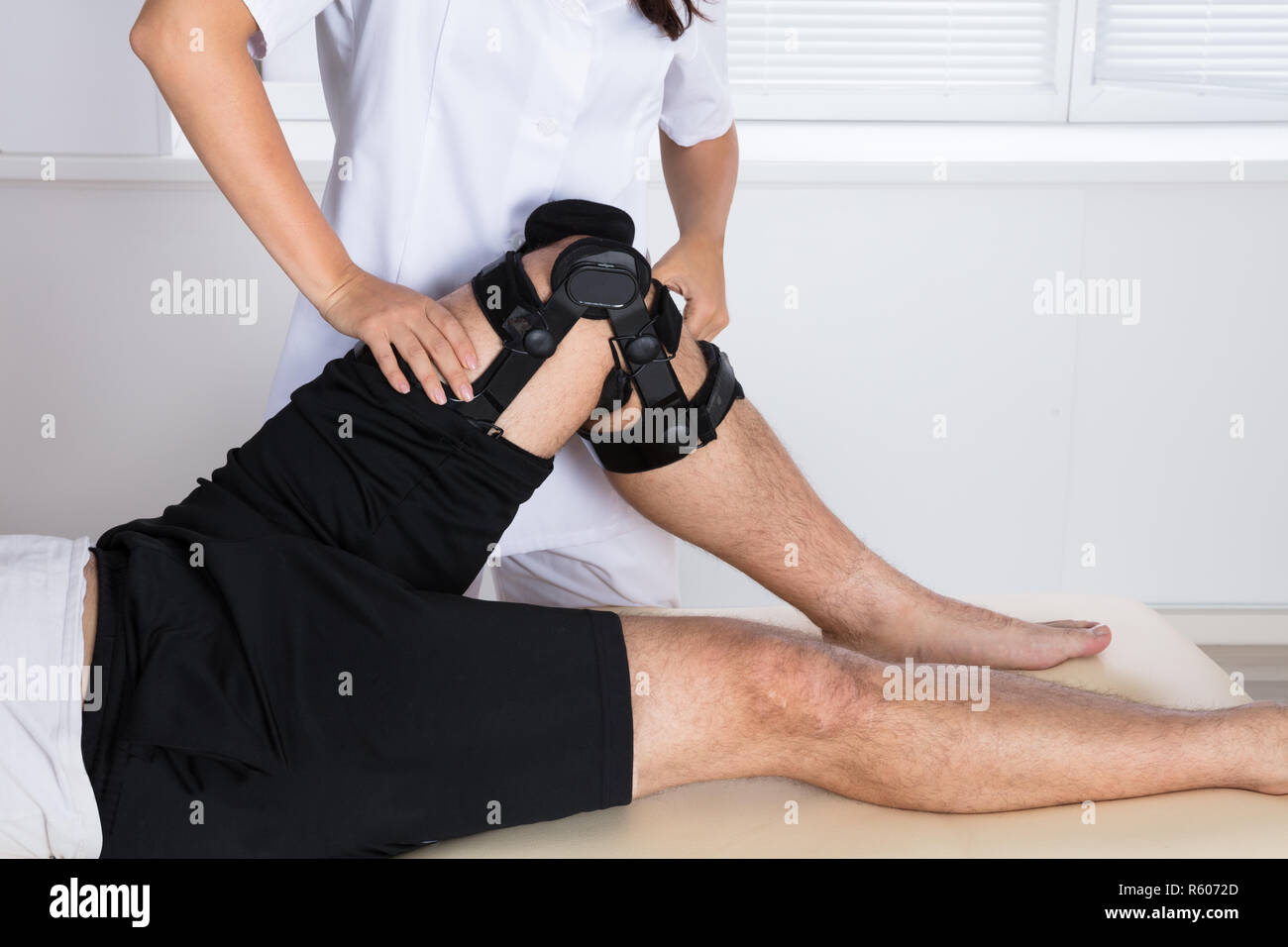 Physiotherapist Fixing Knee Braces On Man's Leg Stock Photo - Alamy
