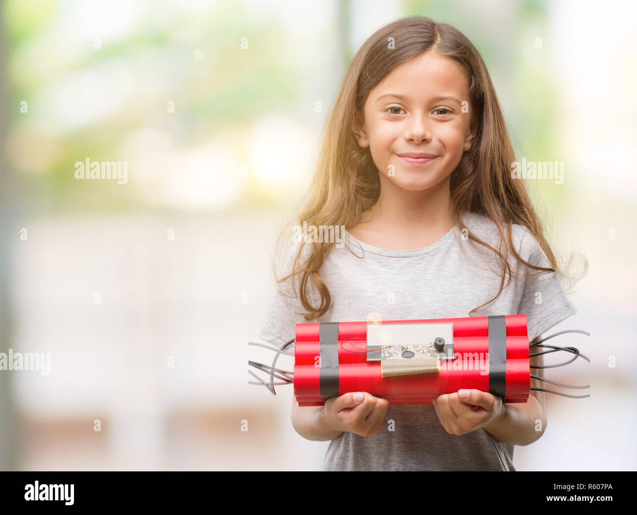 Brunette hispanic girl holding a bomb with a happy face standing and ...