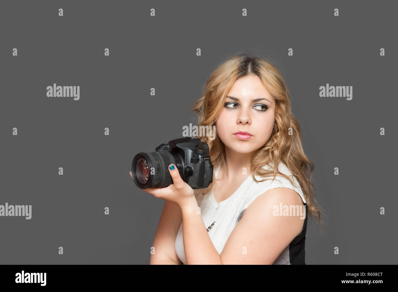 Serious young woman is holding a camera Stock Photo - Alamy