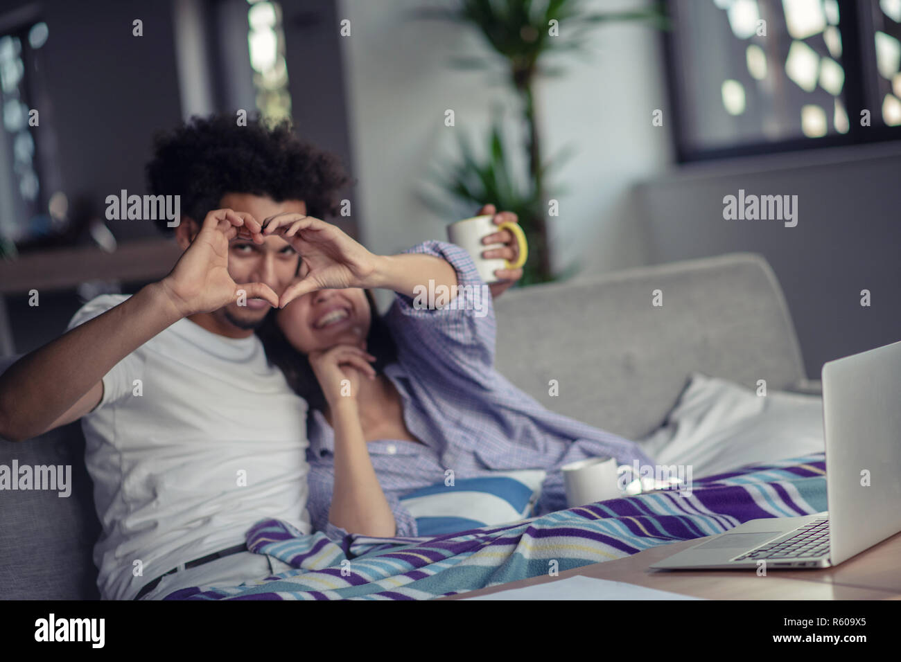 Young couple with laptop lying on a hotel bed hi-res stock photography ...
