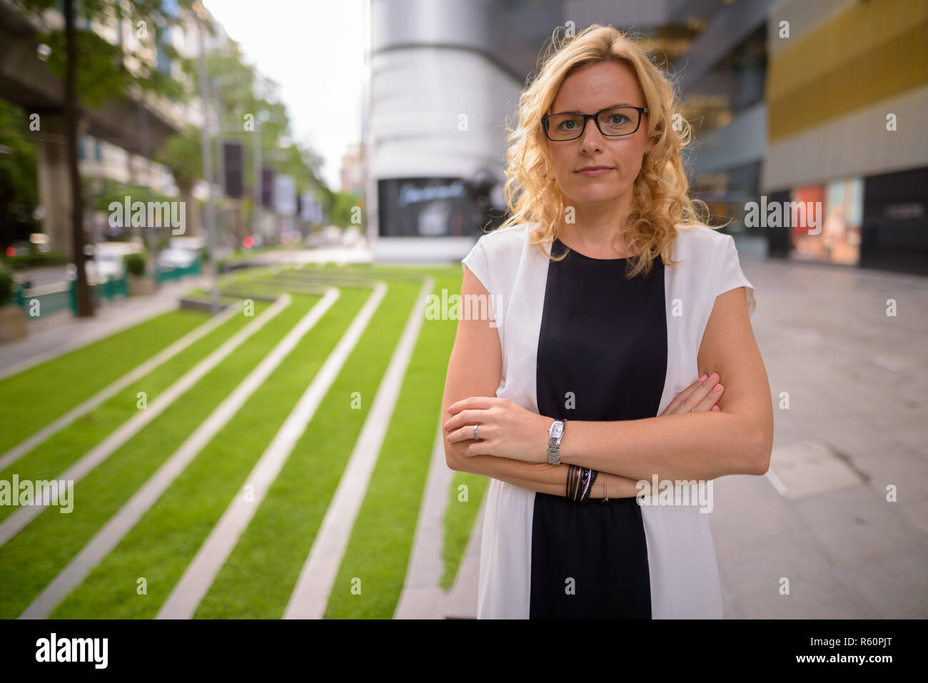 Portrait of beautiful blonde businesswoman wearing eyeglasses outdoors ...