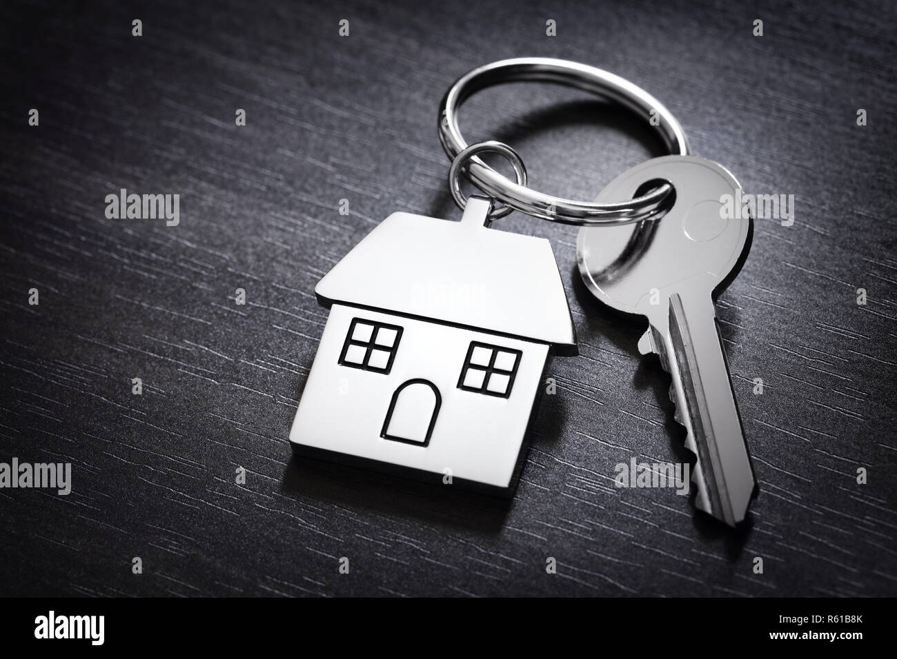 House keys on a house shaped keychain resting on wood background ...
