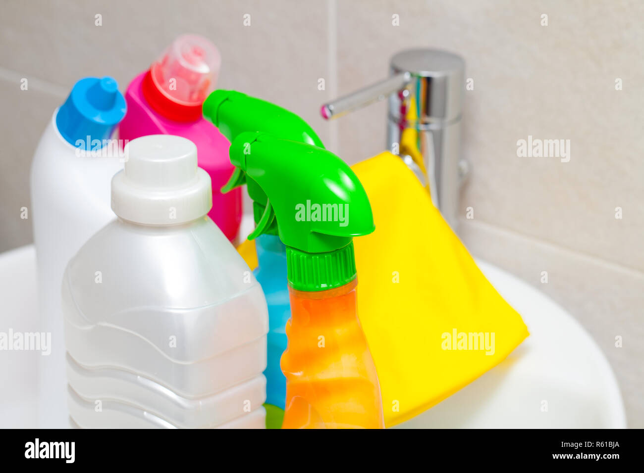 Colorful bottles of cleaning products and yellow latex gloves in the ...