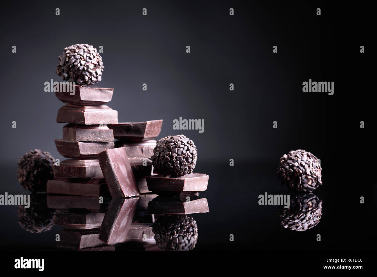 Chocolate candies with broken chocolate pieces on black reflective ...