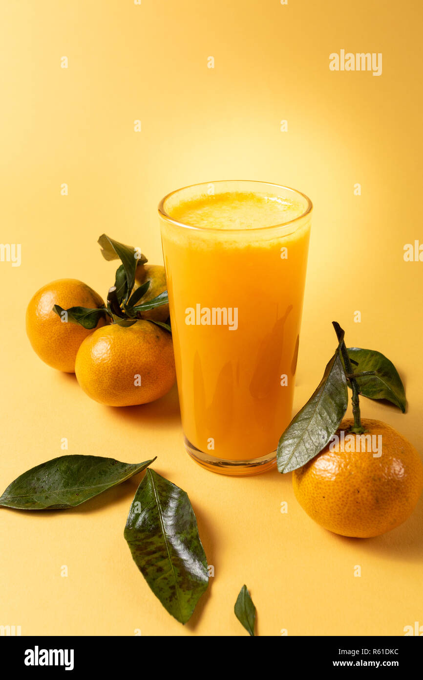 Orange juice in a glass and ripe mandarin or tangerine fruit with green ...