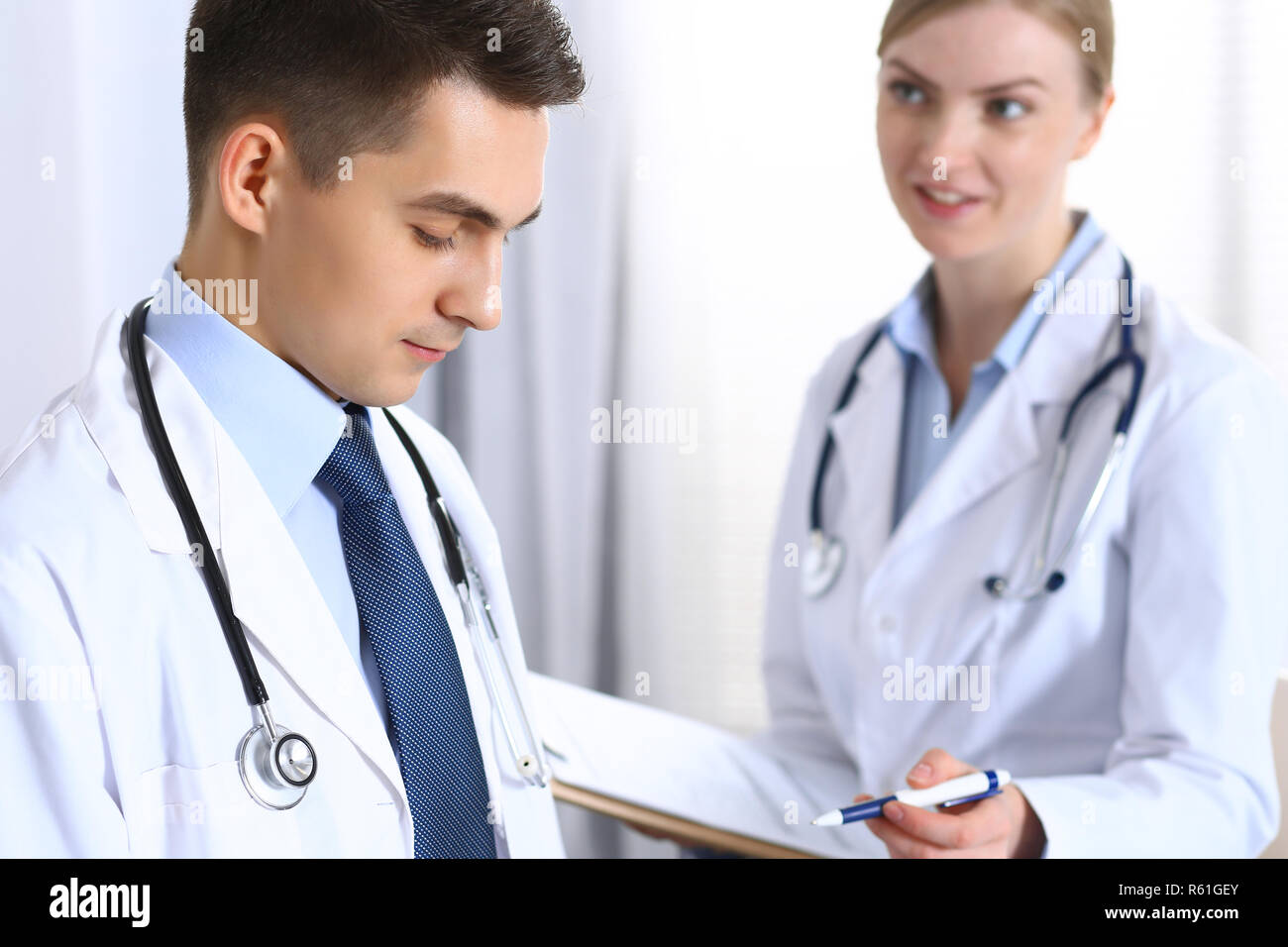 Doctors writing papers using clipboard. Physicians discussing ...