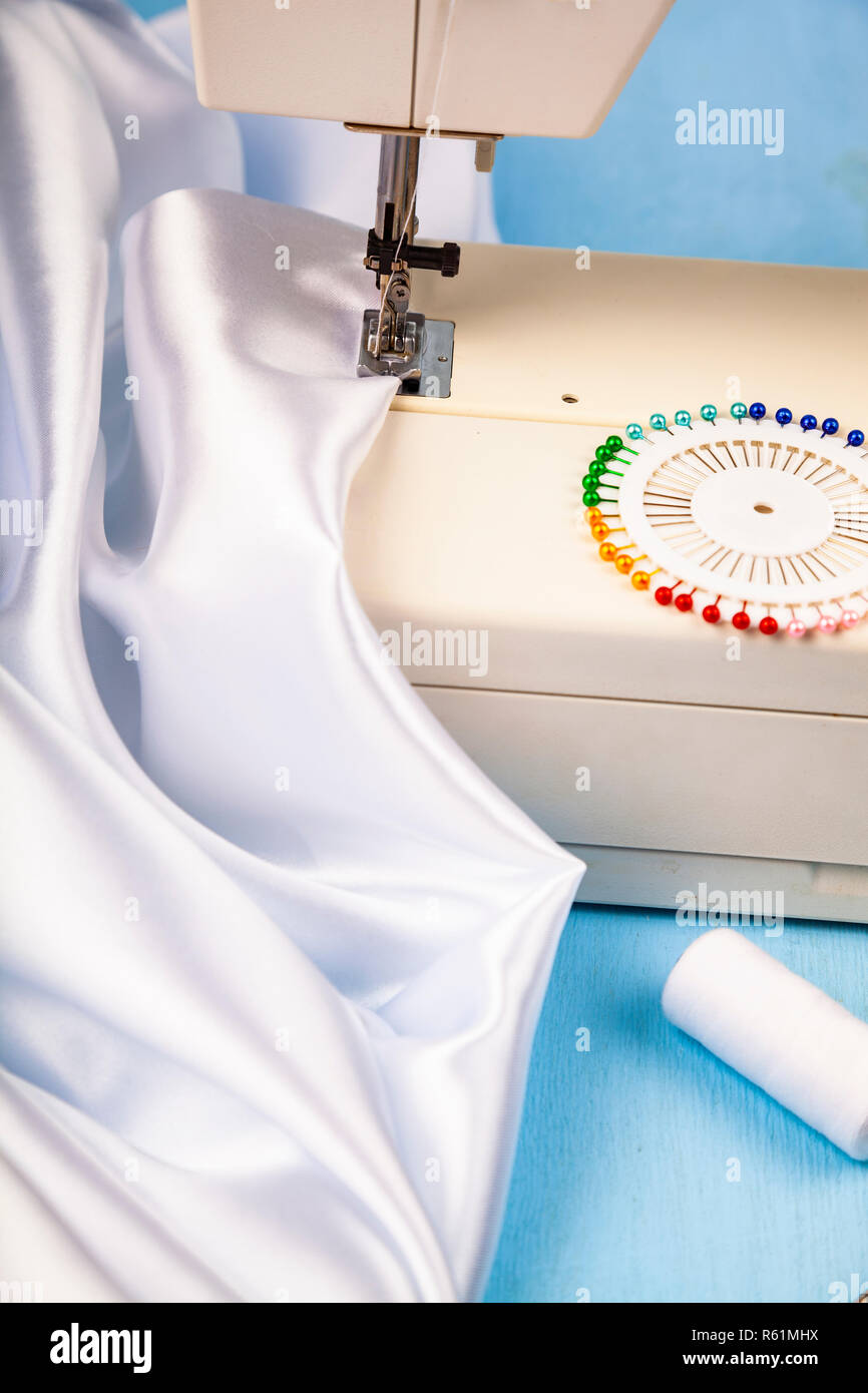 Sewing machine and white satin fabric close-up Stock Photo - Alamy