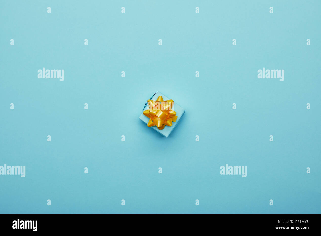 Top view of bright gift box with golden bow on blue background Stock ...